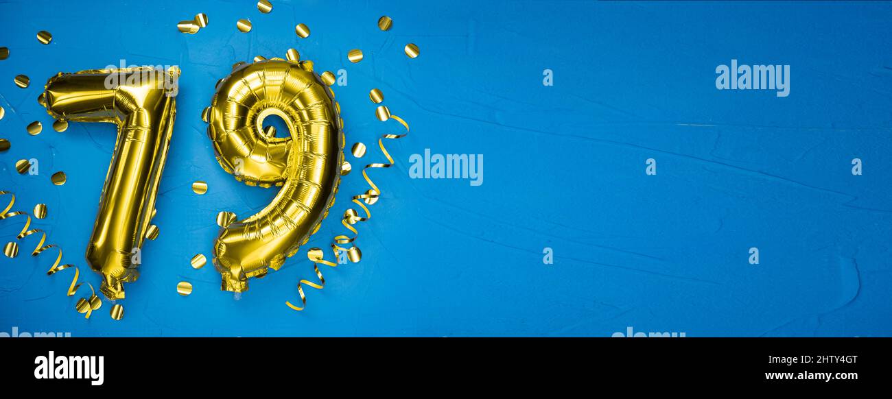 golden yellow foil balloon on blue concrete background number seventy nine. Birthday or ...