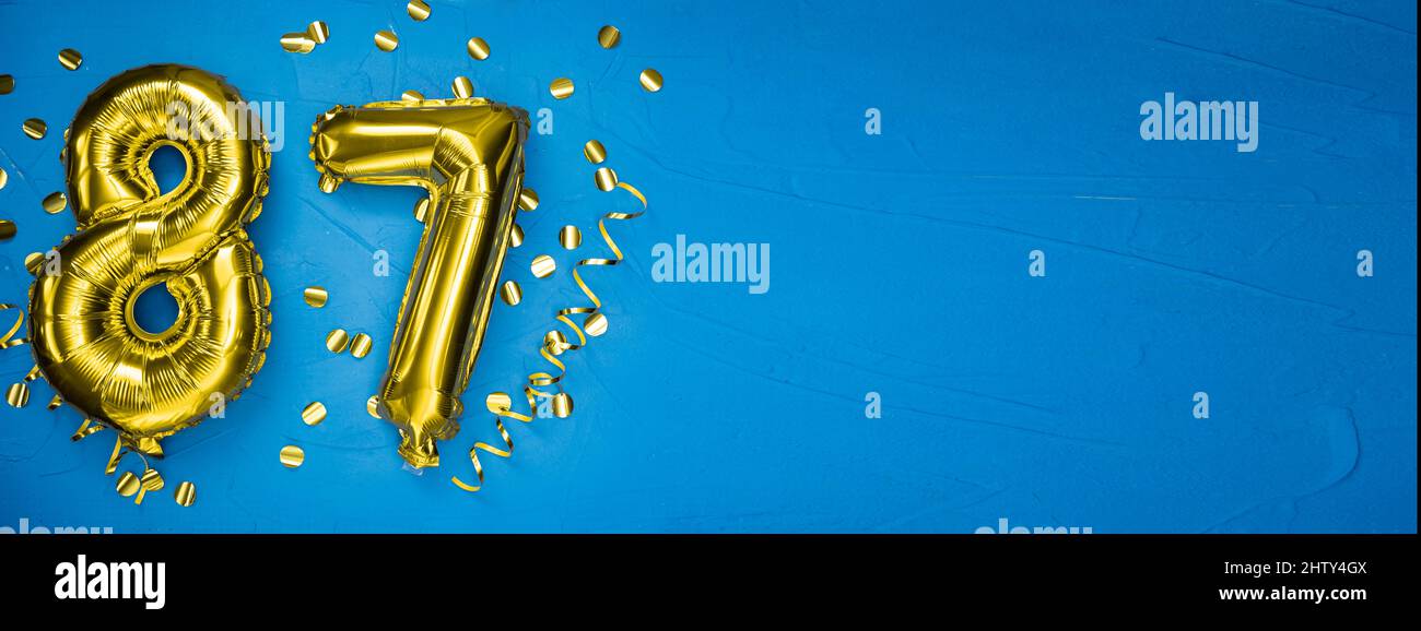 golden yellow foil balloon on blue concrete background number eighty ...