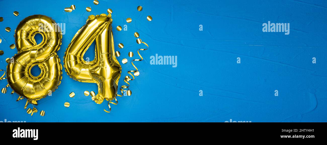 golden yellow foil balloon on blue concrete background number eighty ...