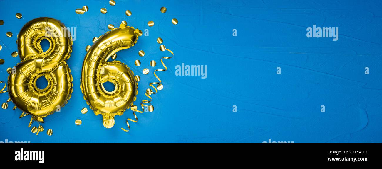 golden yellow foil balloon on blue concrete background number eighty ...