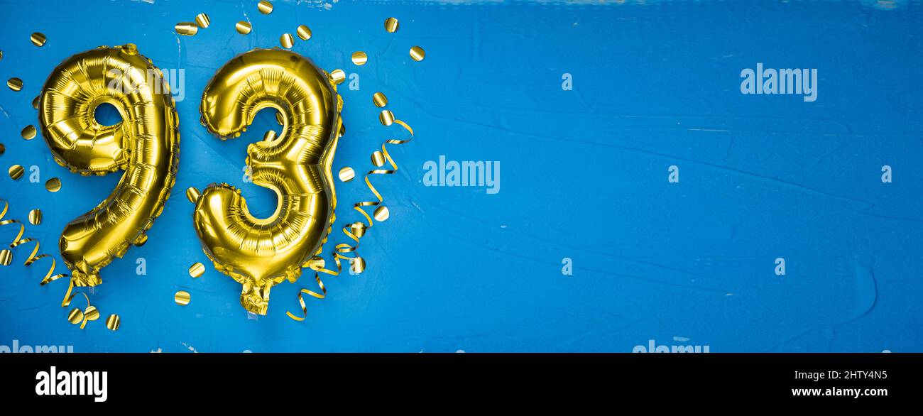 golden yellow foil balloon on blue concrete background number ninety ...