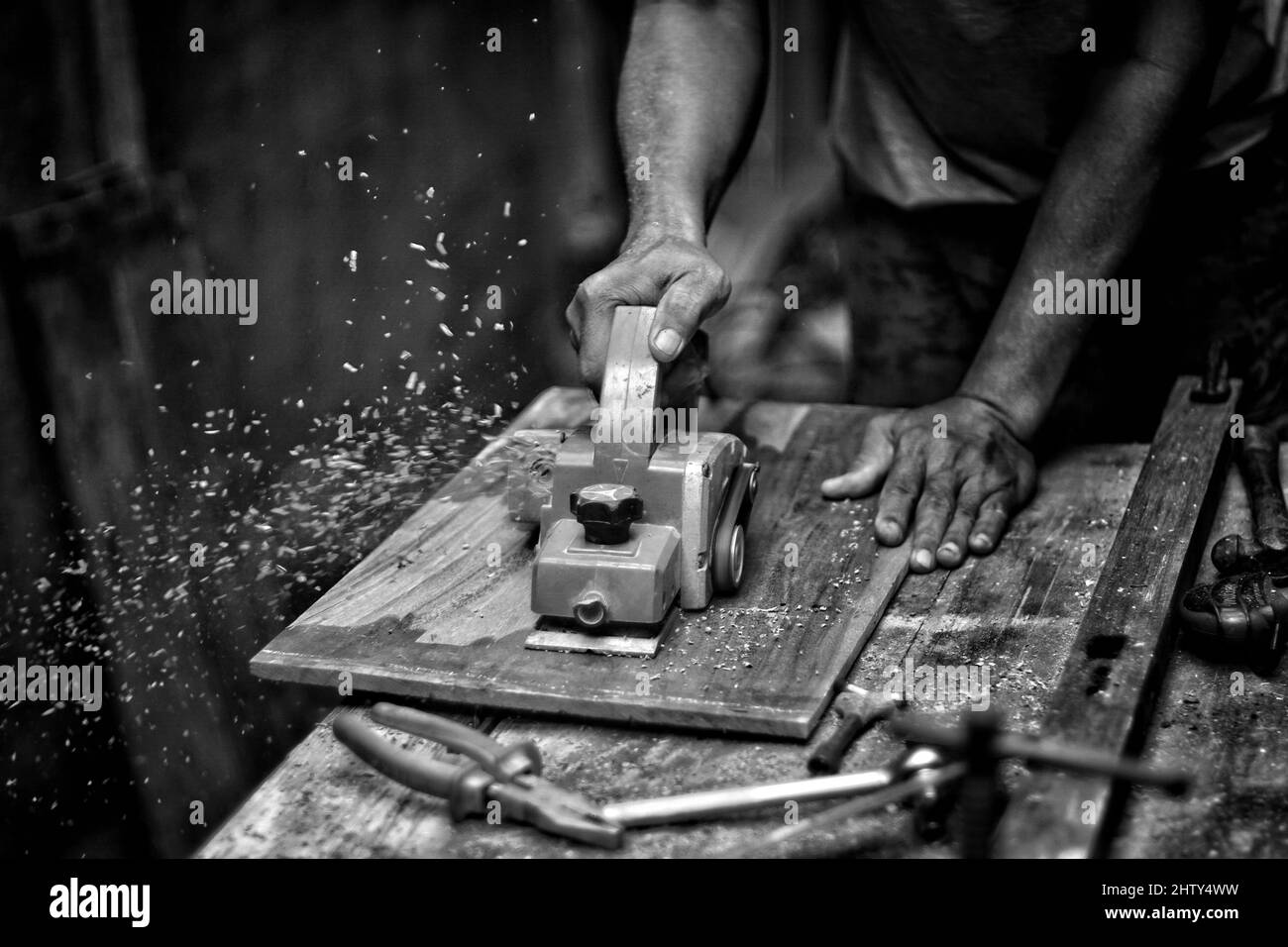 Grayscale shot of a carpenter working with a plane on the wood Stock ...