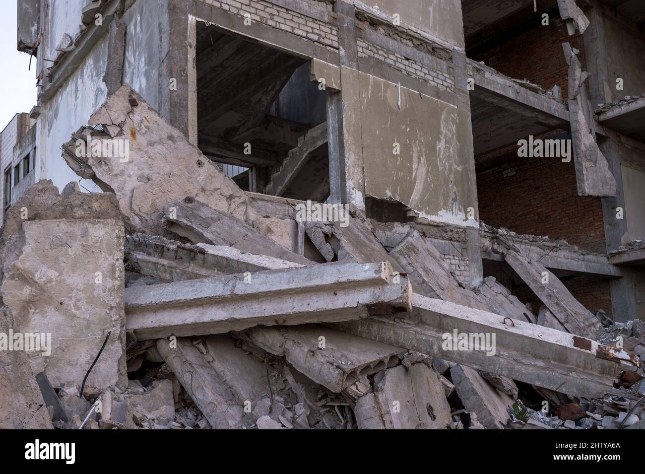 A large destroyed building with a pile of gray concrete fragments of ...