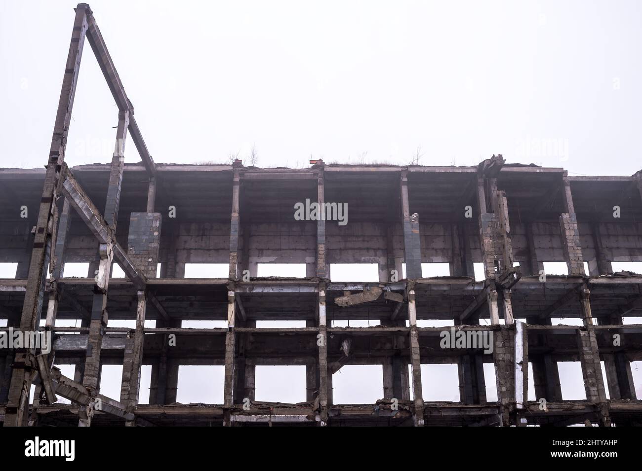 The frame of a large ruined building in the fog against a gray sky in a ...