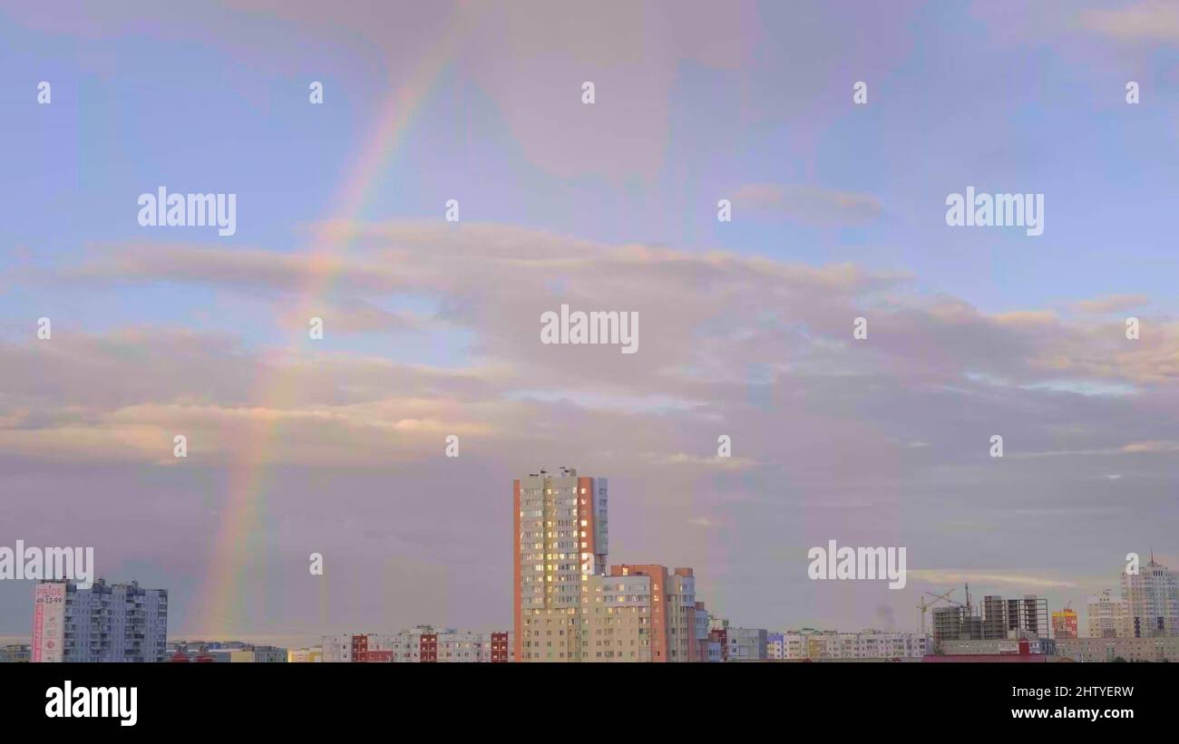 Multicolored rainbow and clouds in the sky after the rain and multi storey buildings in the city ...
