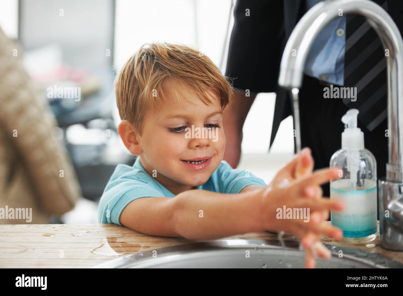 Keeping his hands clean. A cute young boy washing his hands in the ...