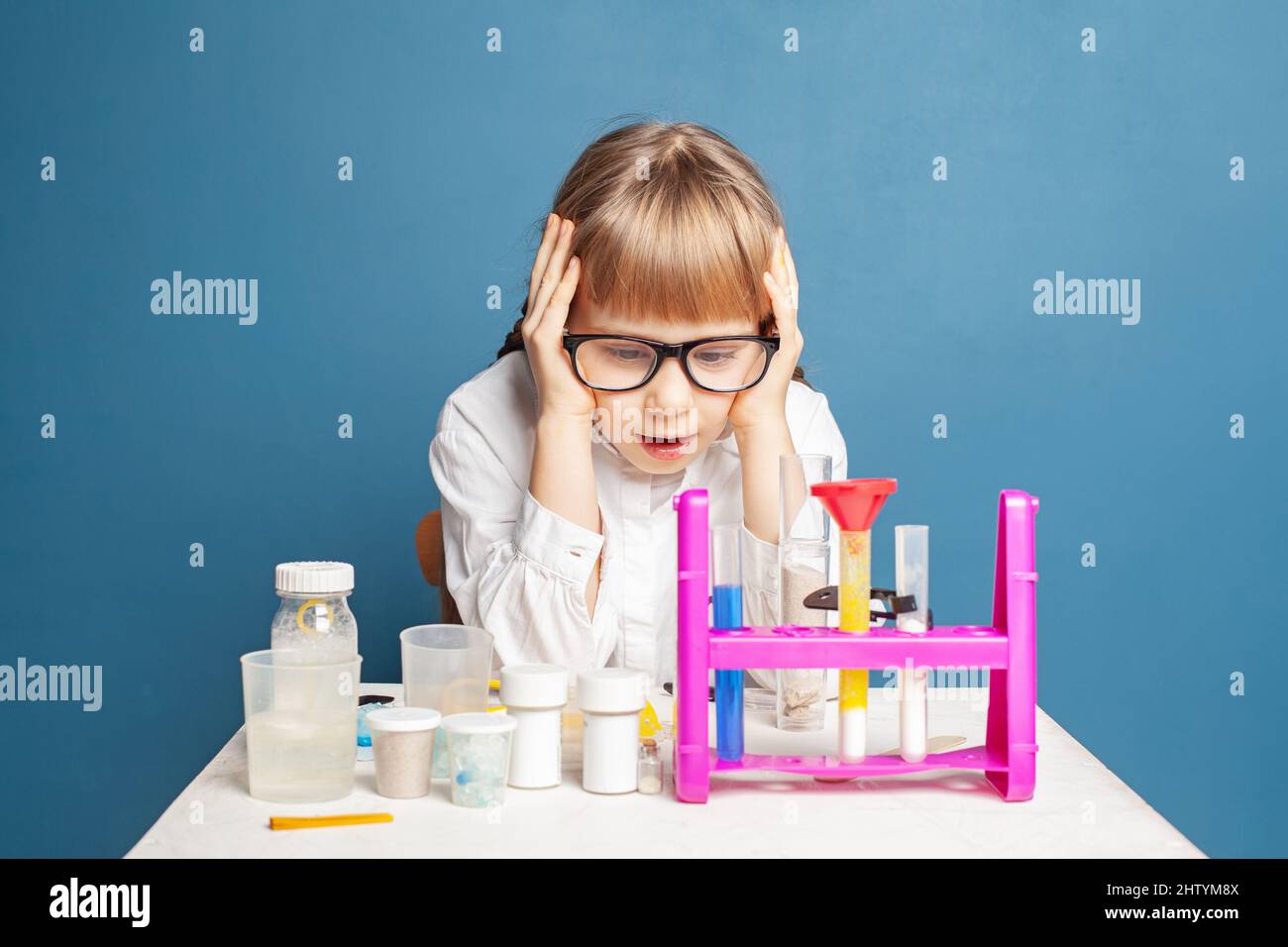 Surprised child girl doing science experiments on blue background ...