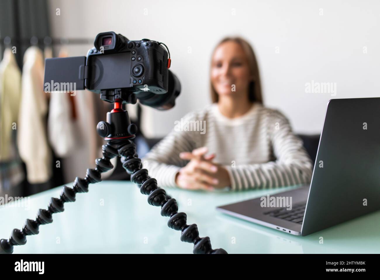 Confident young female vlogger sit at desk shooting live broadcast on ...