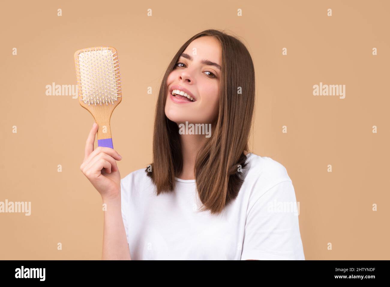 Girl combing hair. Beautiful young woman holding comb straightened hair ...