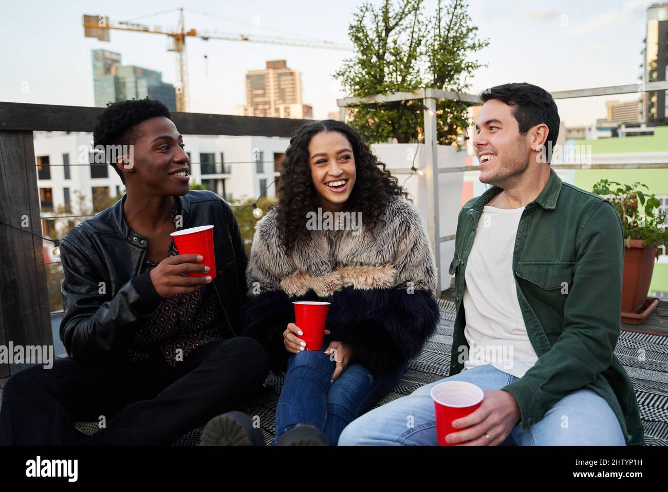 Group of multi-cultural young adults laughing at joke together. Sitting ...