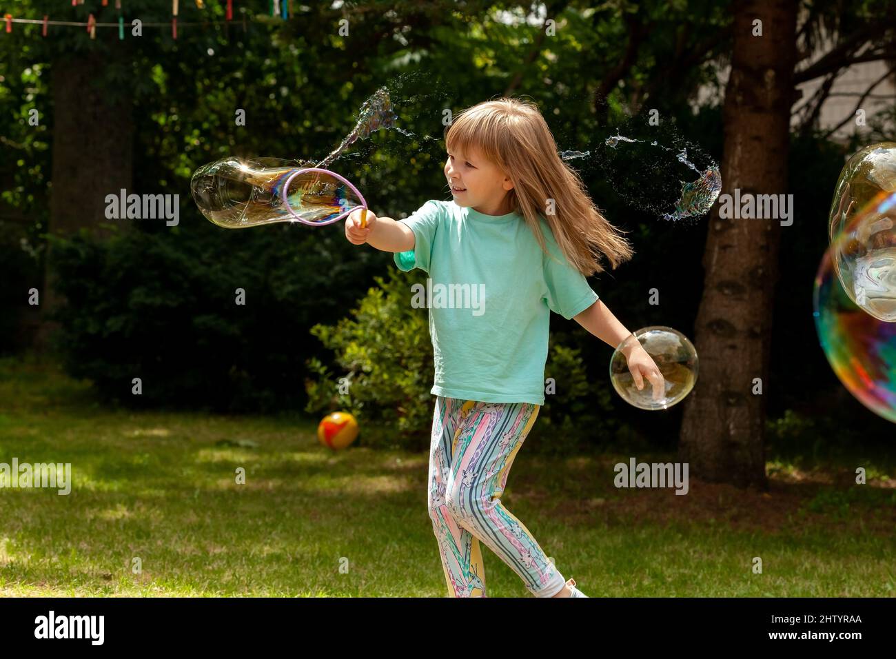 Happy cheerful elementary school age child, girl playing with soap ...