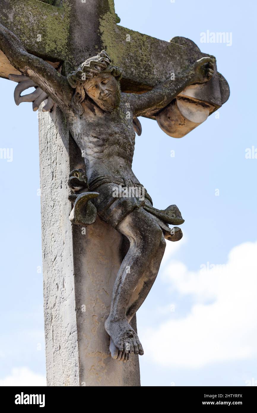 Jesus Christ on the cross old antique stone sculpture covered in moss, cemetery graveyard figure ...