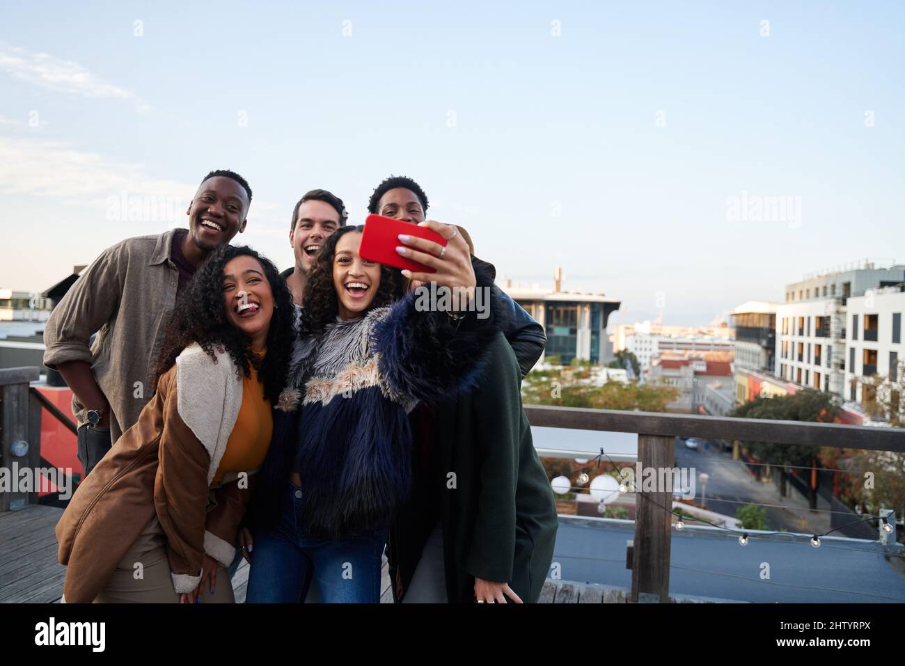 Multi-cultural group of friends taking a selfie at a rooftop party ...