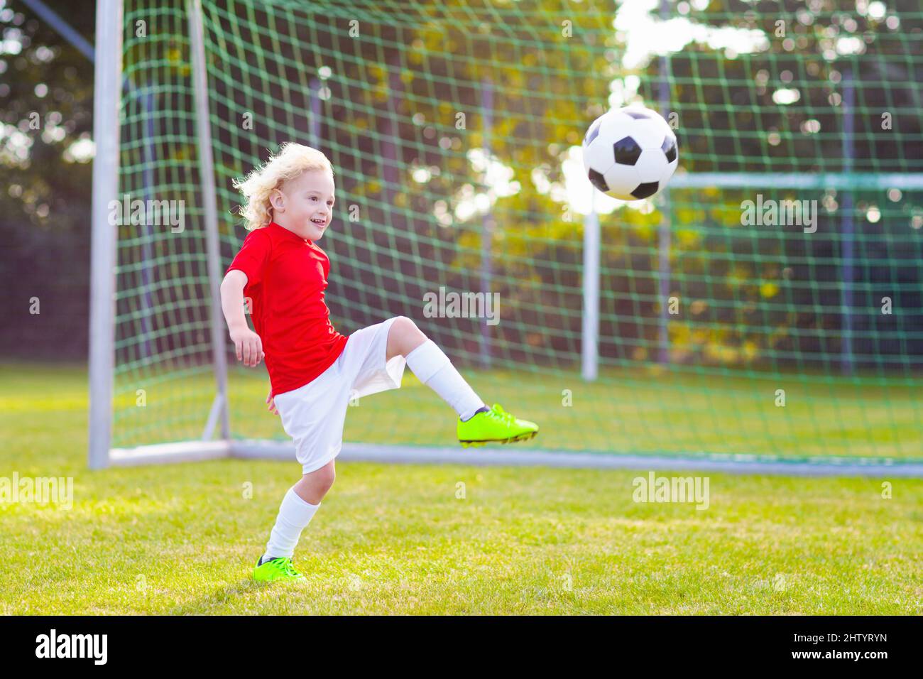 Kids play football on outdoor field. Children score a goal during ...