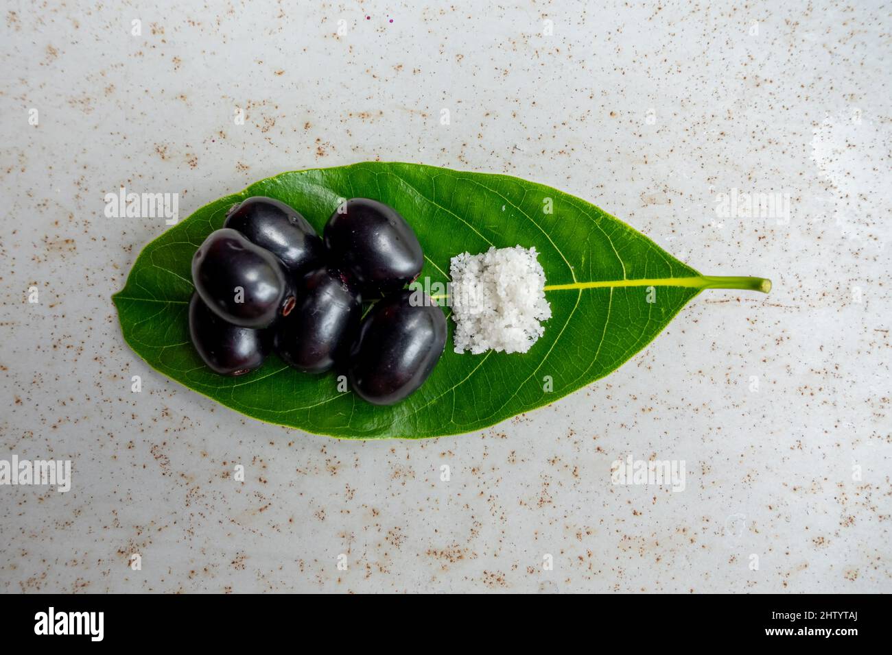Spicy mixed salt with some black java plum fruit in the green leaves. A ...