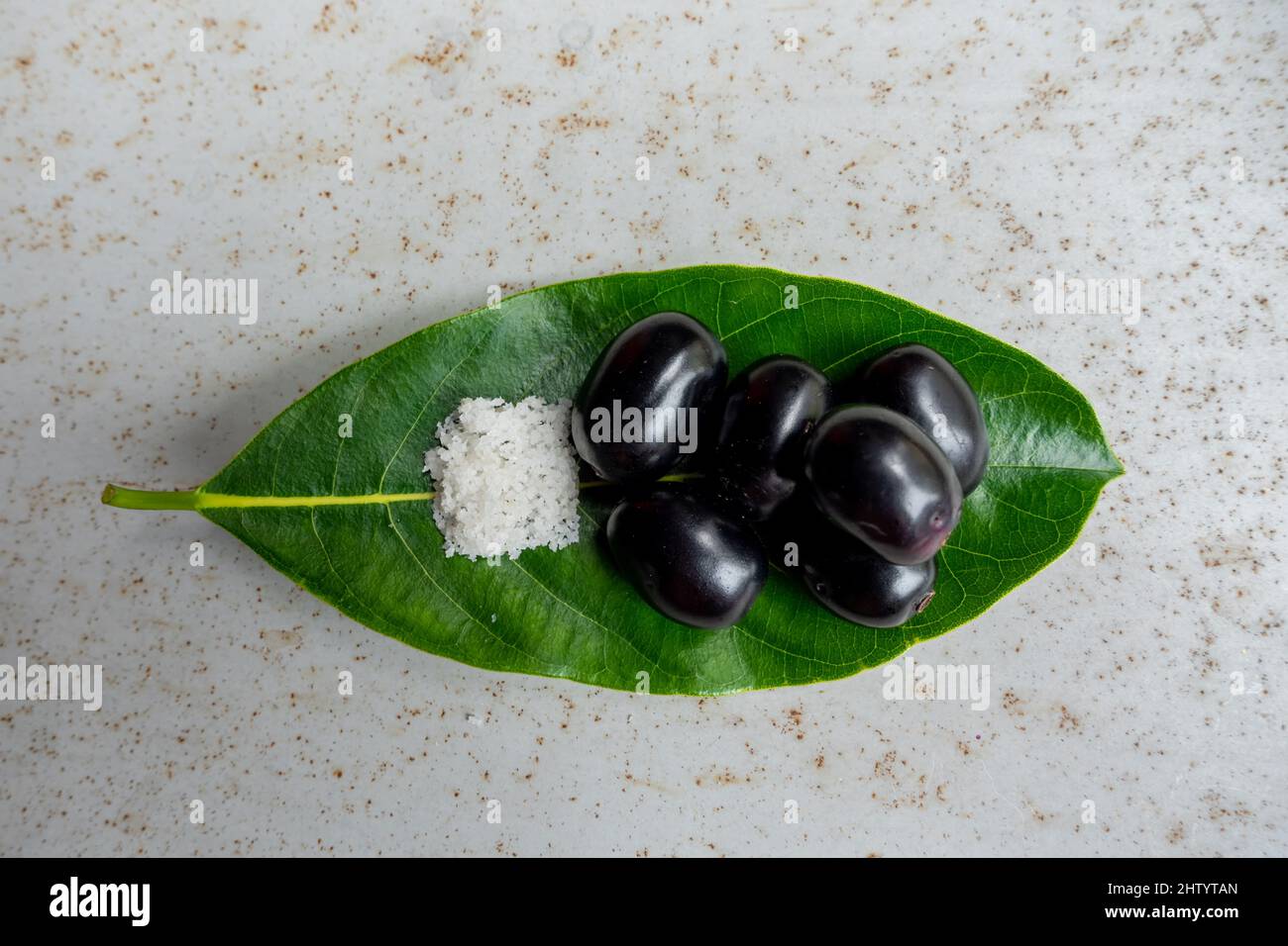 Spicy mixed salt with some black java plum fruit in the green leaves. A ...