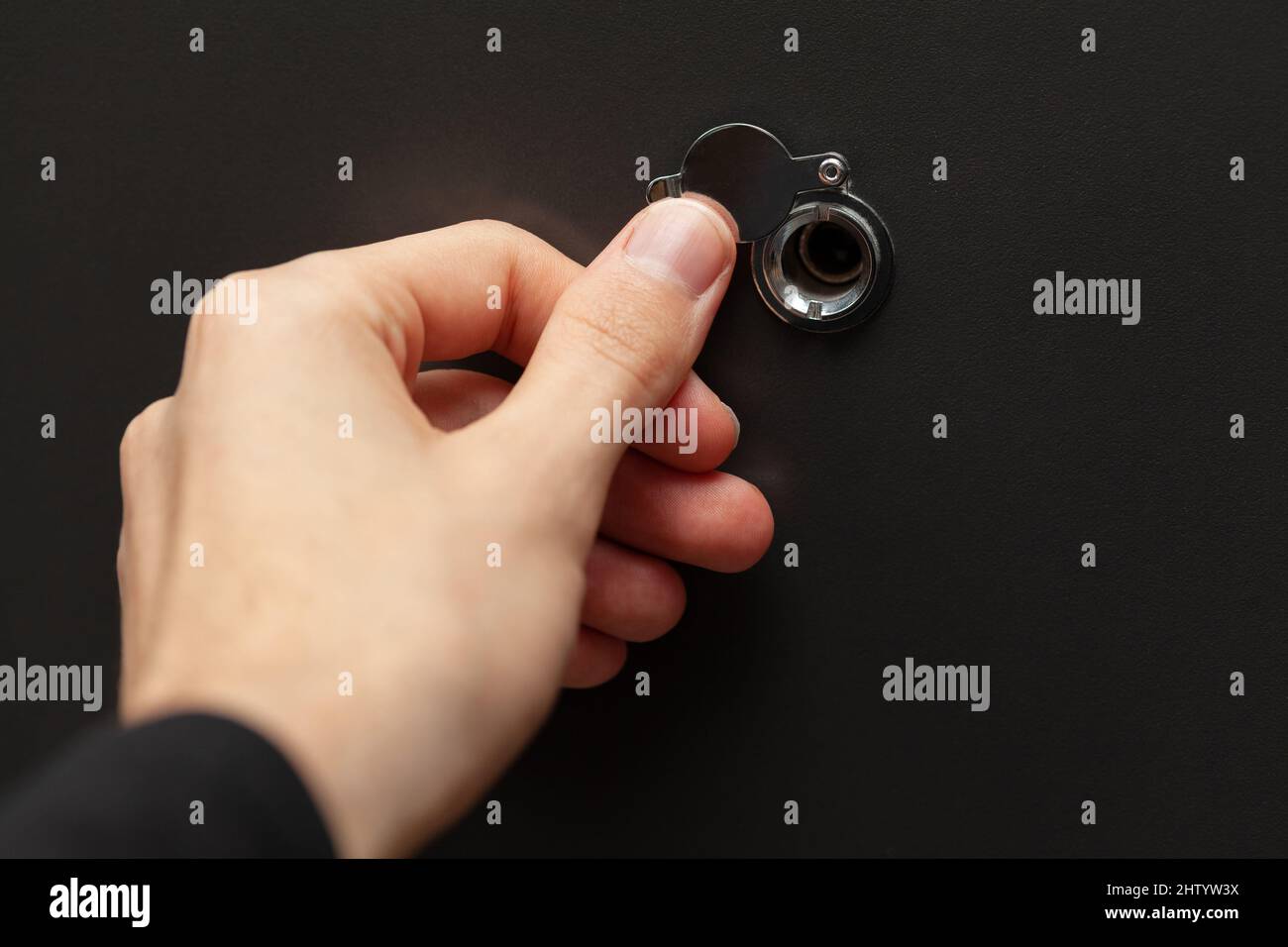 Anonymous man taking a peek, looking through a peephole checking the ...