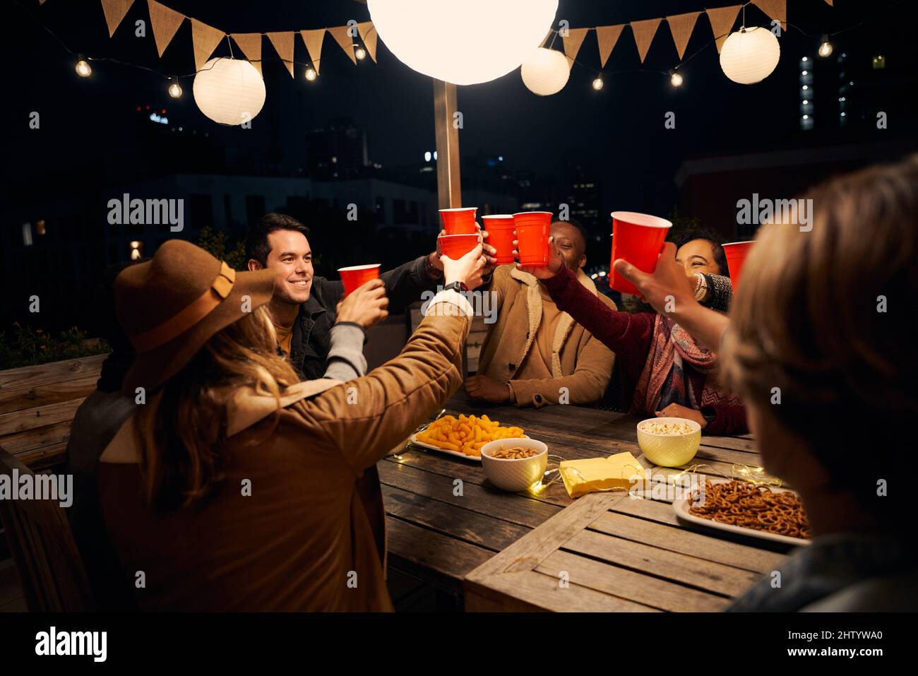 Group of diverse friends sitting, making a toast at an outdoor party ...