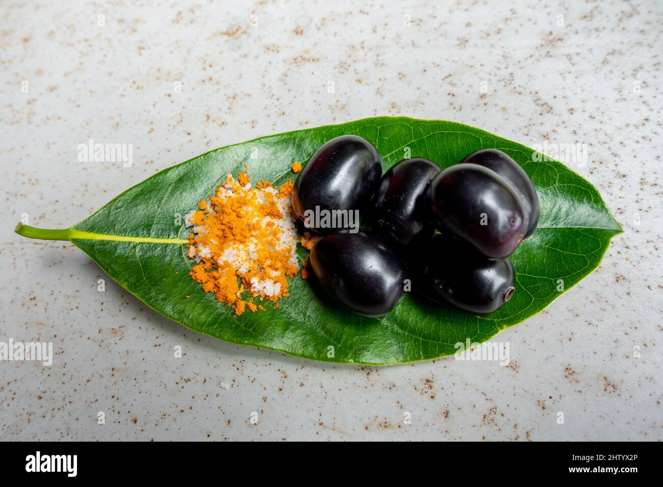 Spicy mixed salt with some black java plum fruit in the green leaves. A ...