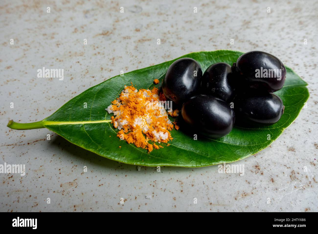 Spicy mixed salt with some black java plum fruit in the green leaves. A ...
