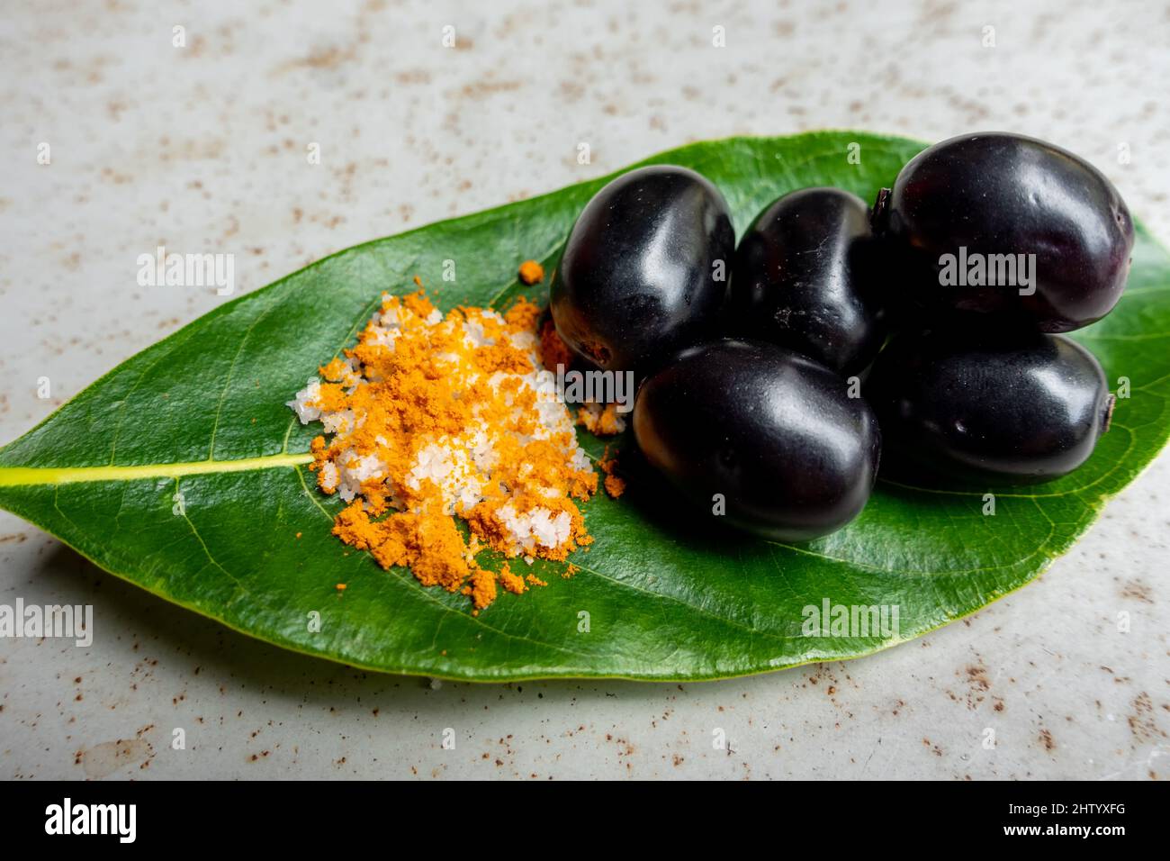 Spicy mixed salt with some black java plum fruit in the green leaves. A ...