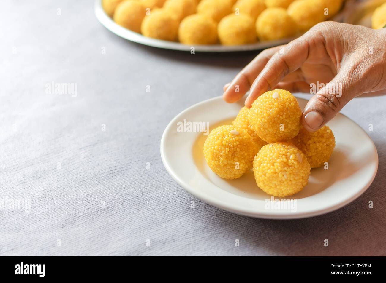 Bundi laddu with human hand keeping it in the white plate. Used ...