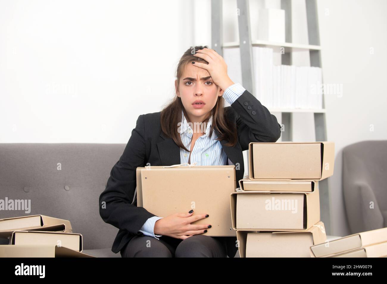 Busy young businesswoman with many folders of documents, frustration ...