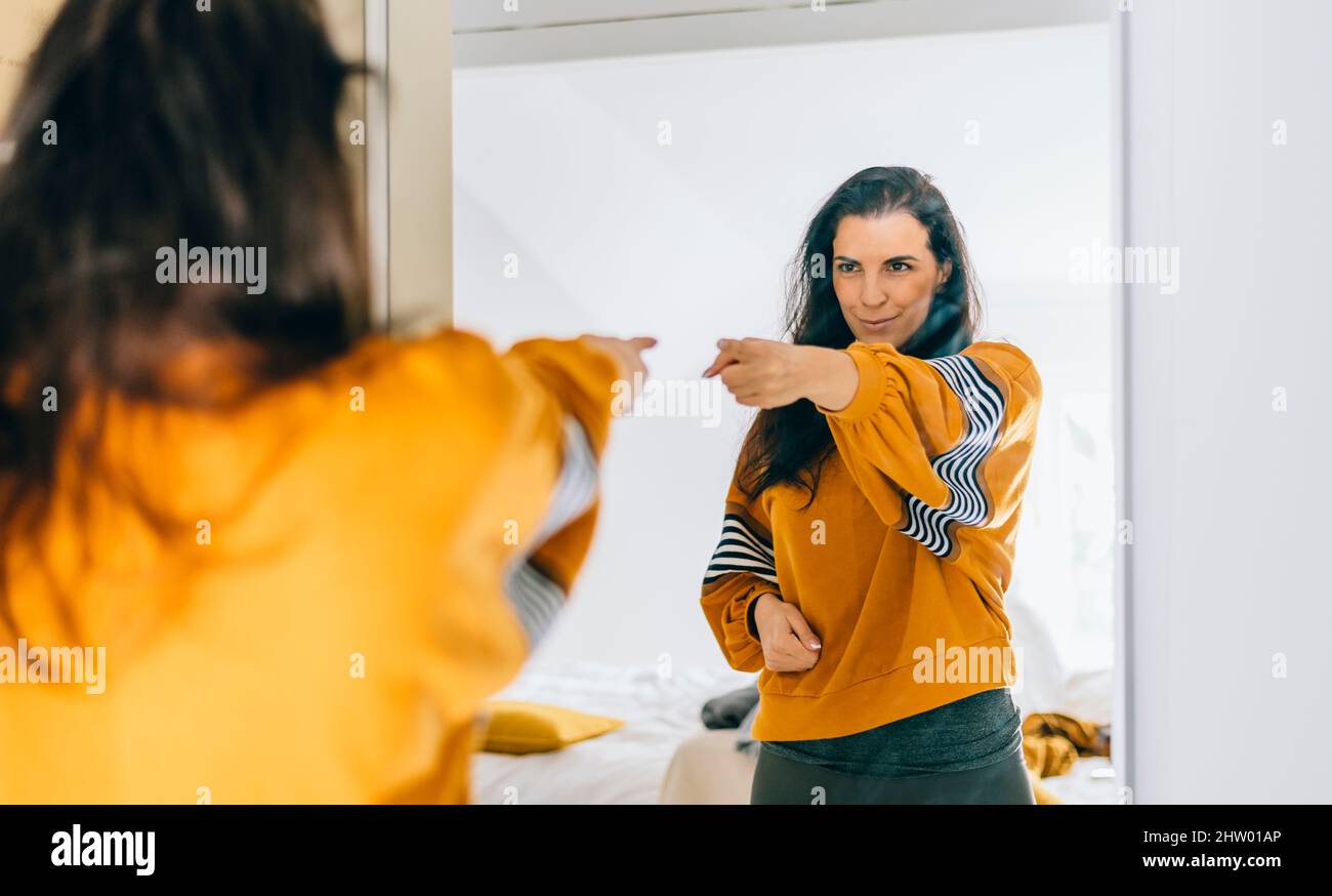 Self confident single woman pointing finger at her reflection in mirror ...