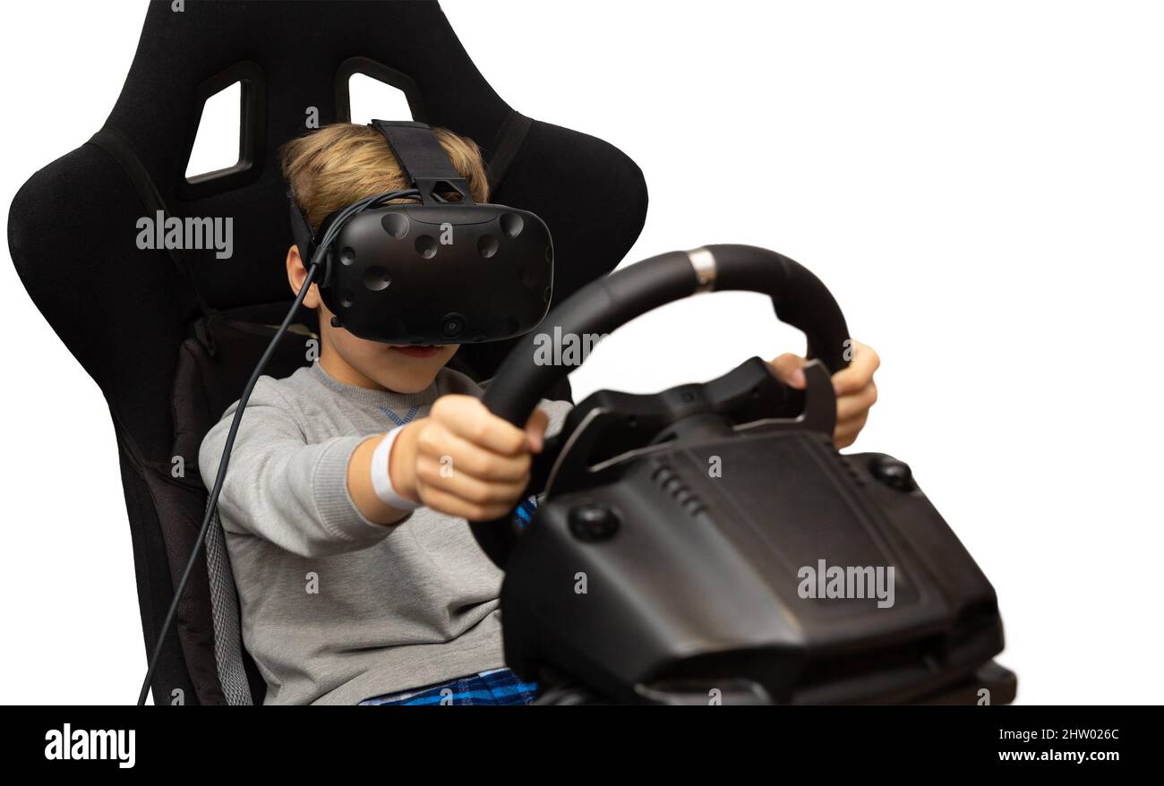 The boy plays on the racing simulator in glasses of a virtual reality ...