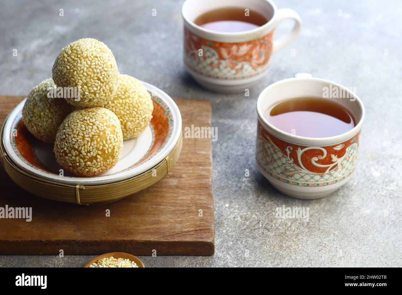 Onde Onde or glutinous rice cake sesame ball on ceramic plate with cups ...