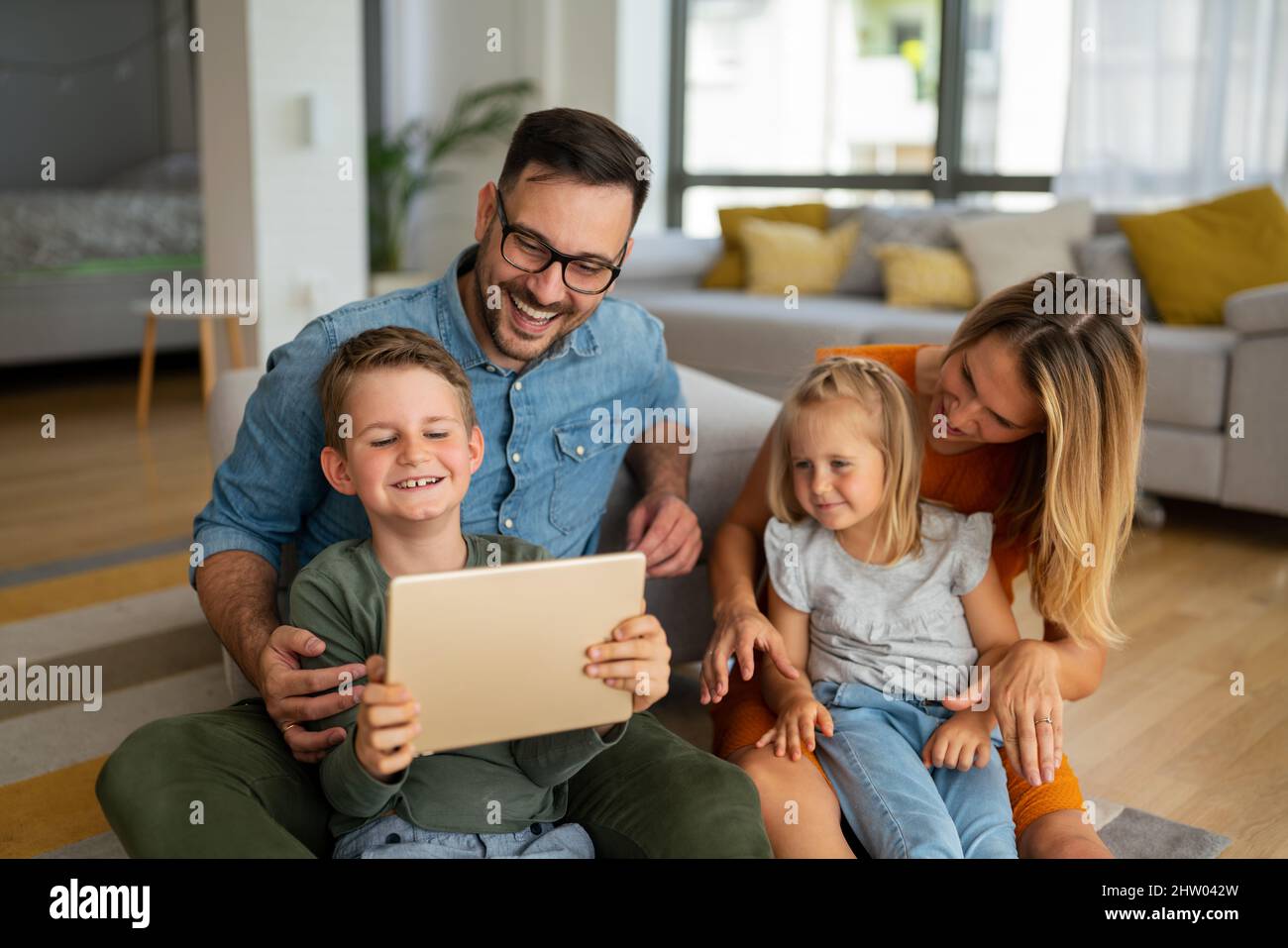 Happy young family having fun time at home. Parents with children using ...