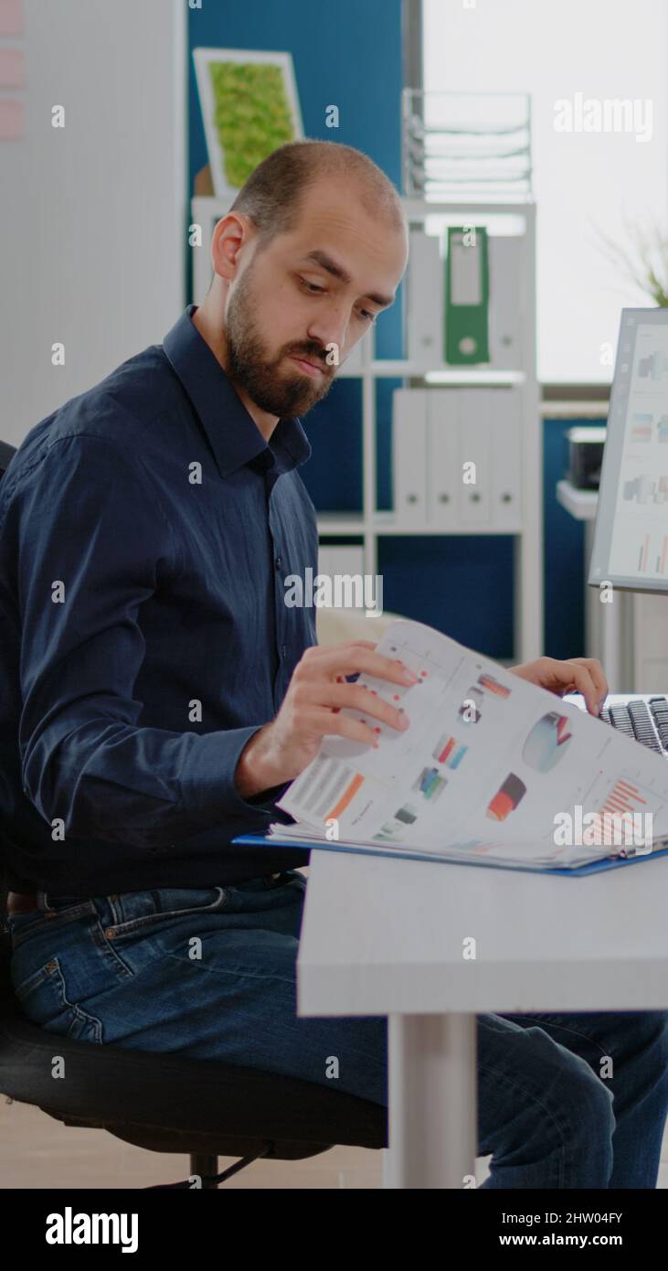 Business manager using computer and papers with charts for marketing ...