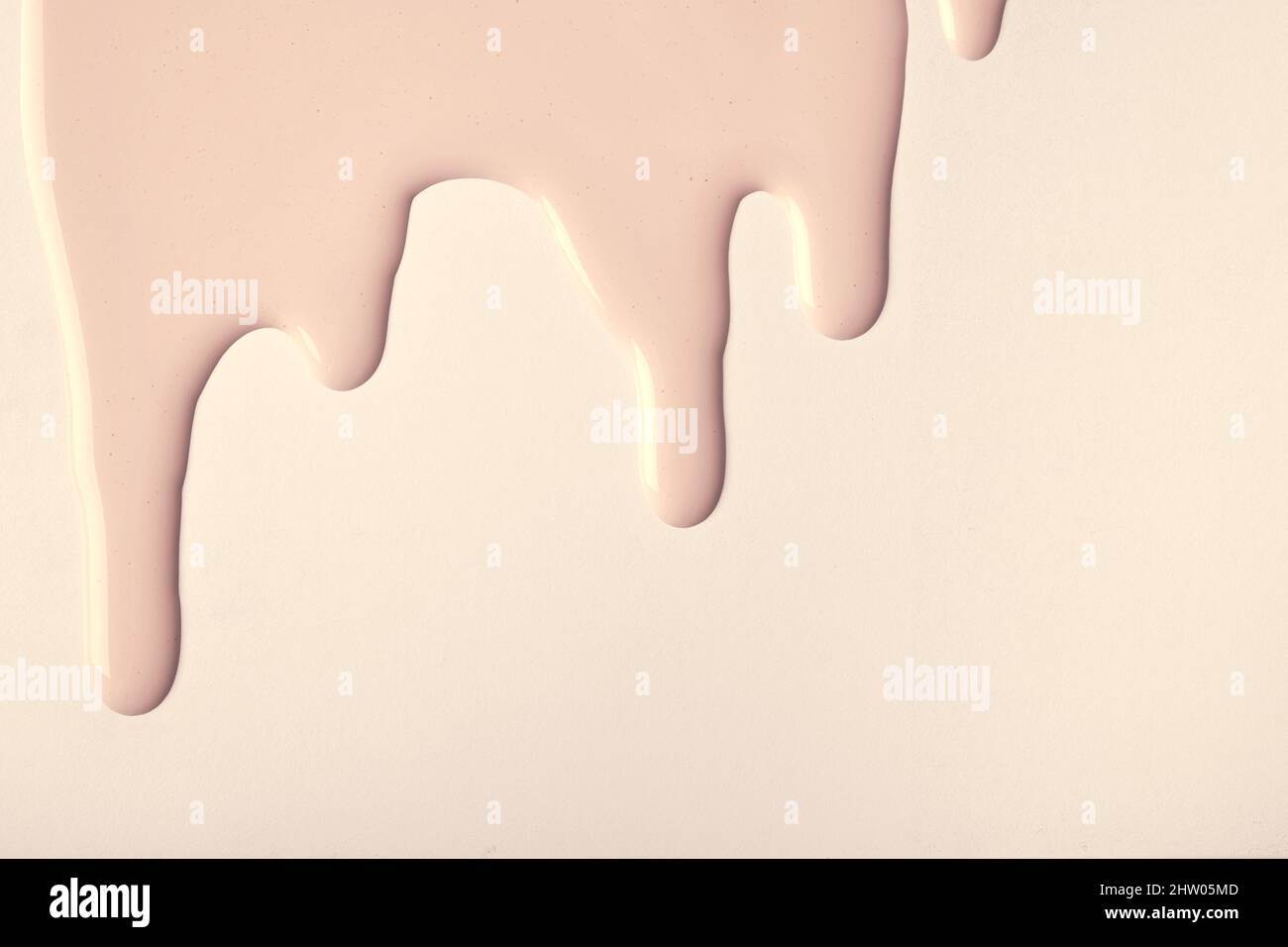 Light brown liquid drops of paint color flow down on beige background ...