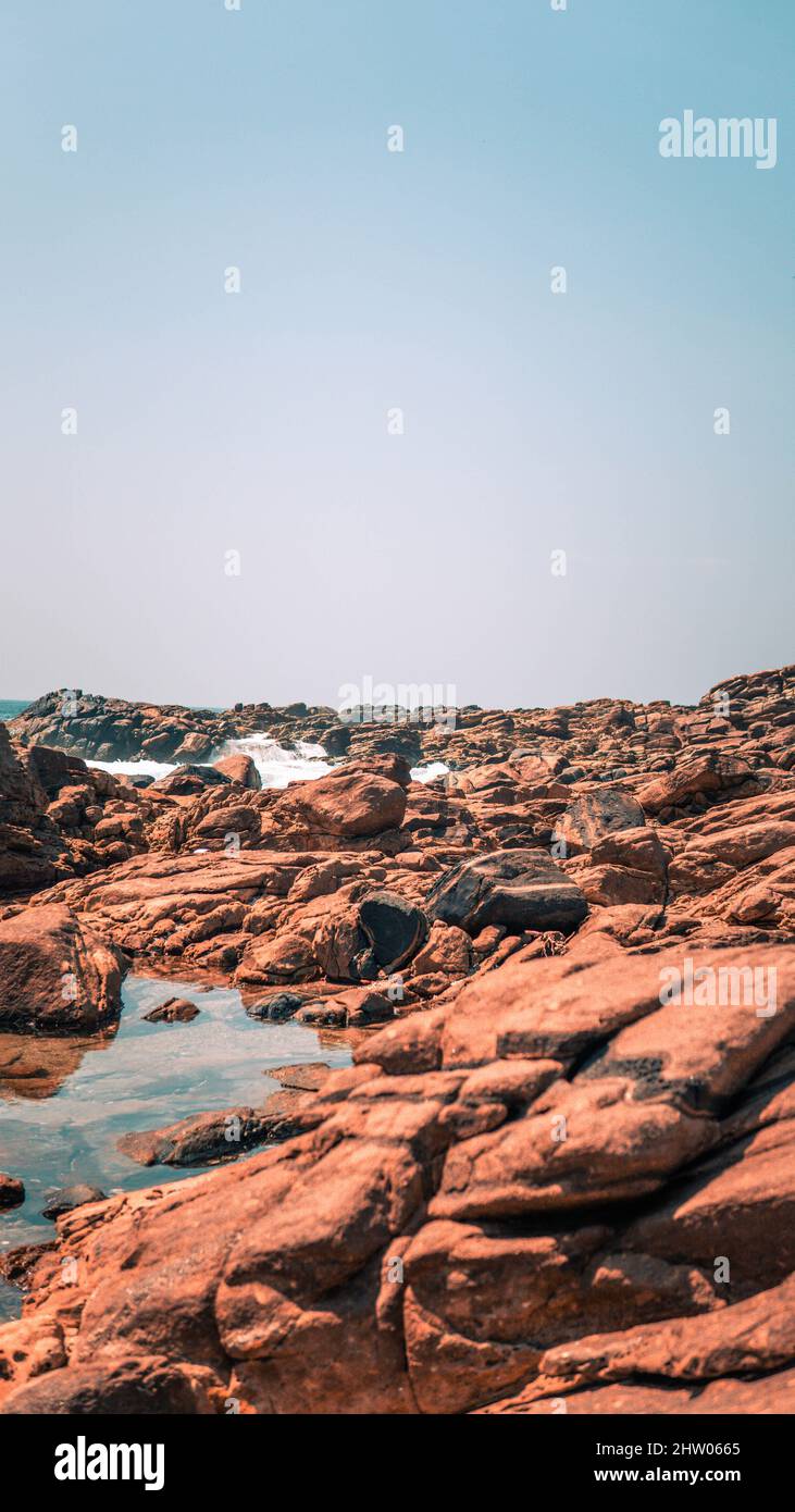 Vertical shot of a rocky beach under the clear skies Stock Photo - Alamy