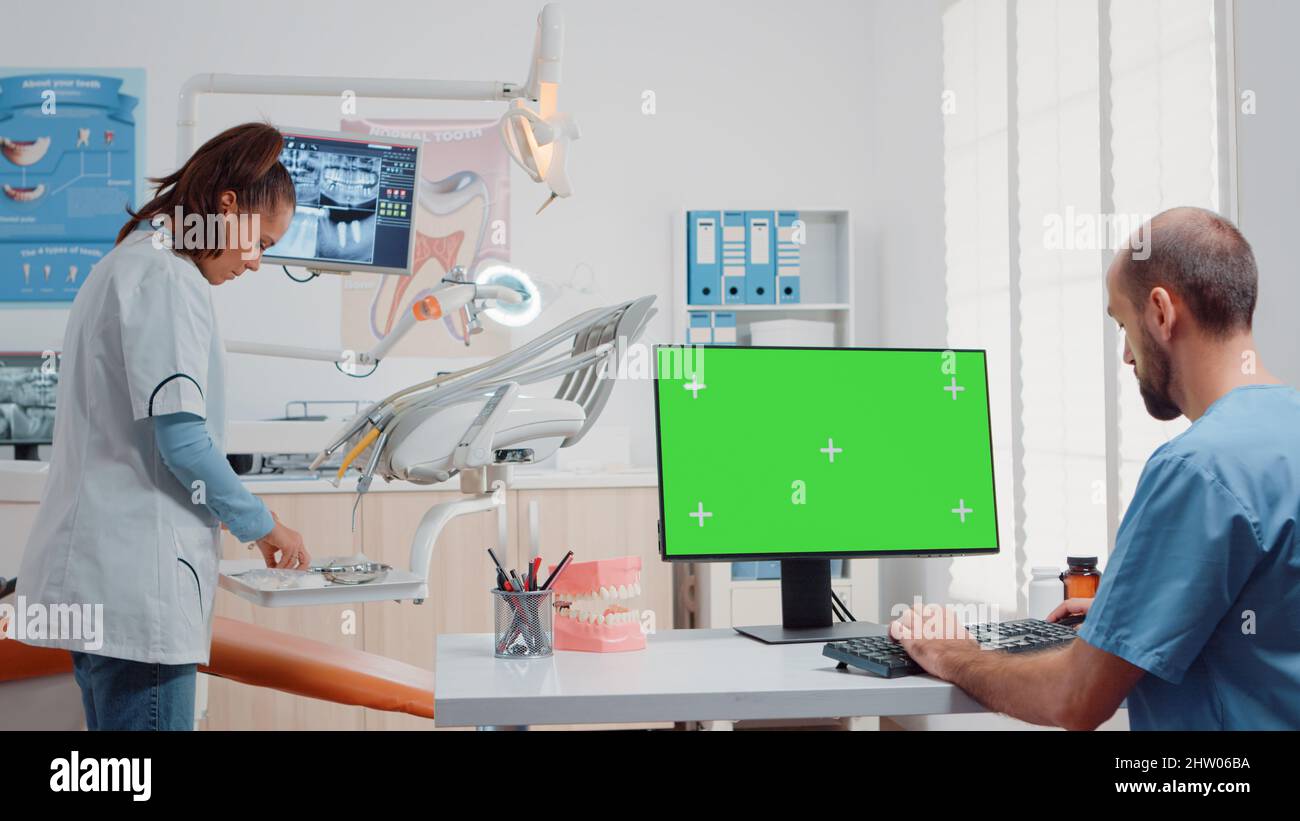 Man using monitor with horizontal green screen and talking to dentist ...