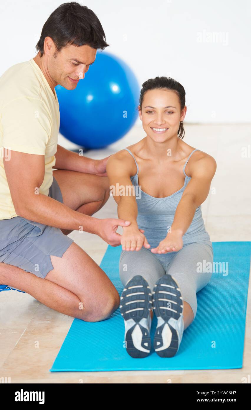 Try to touch your toes. A fitness instructor showing a young woman how ...