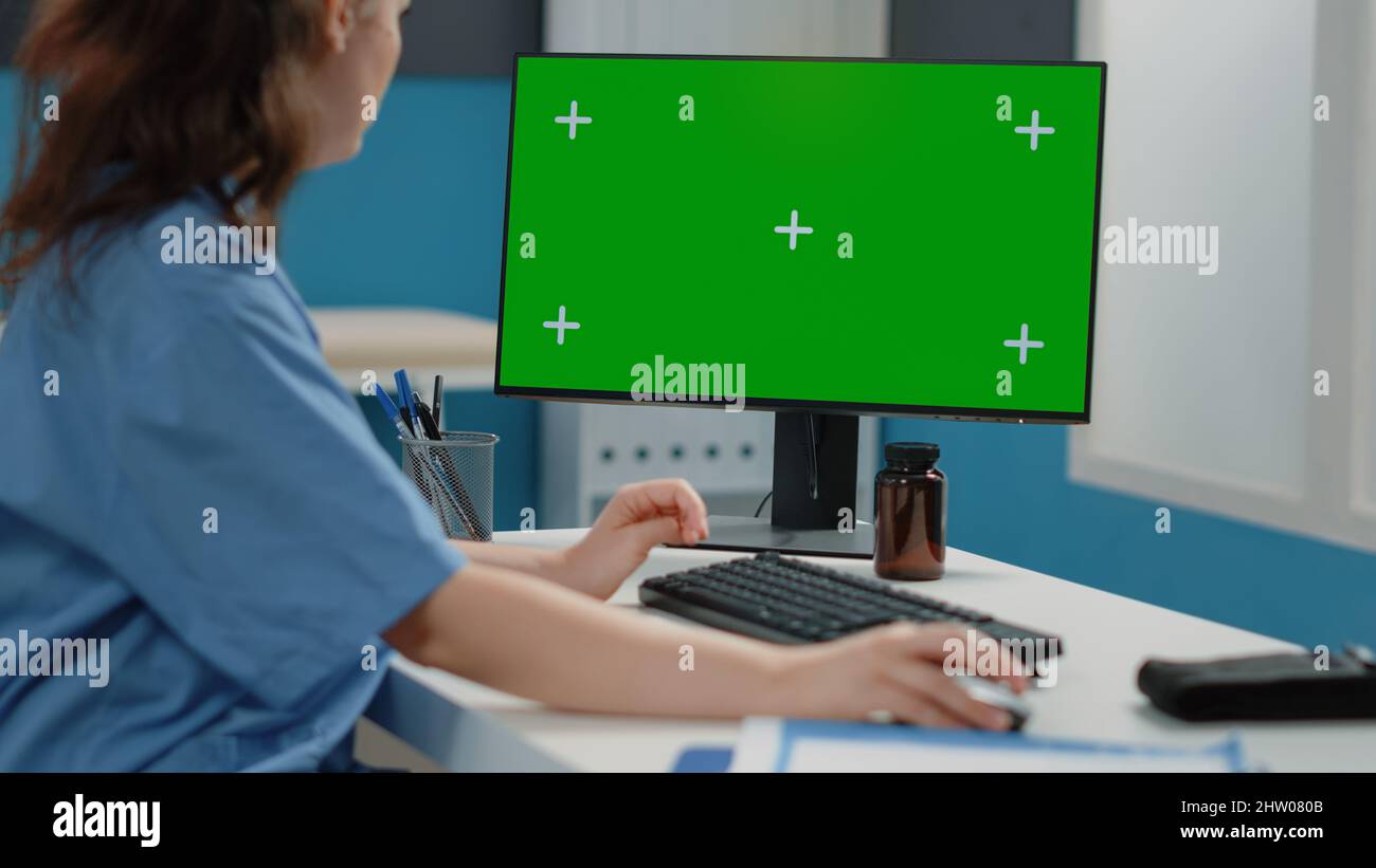 Close up of woman nurse looking at horizontal green screen on computer ...