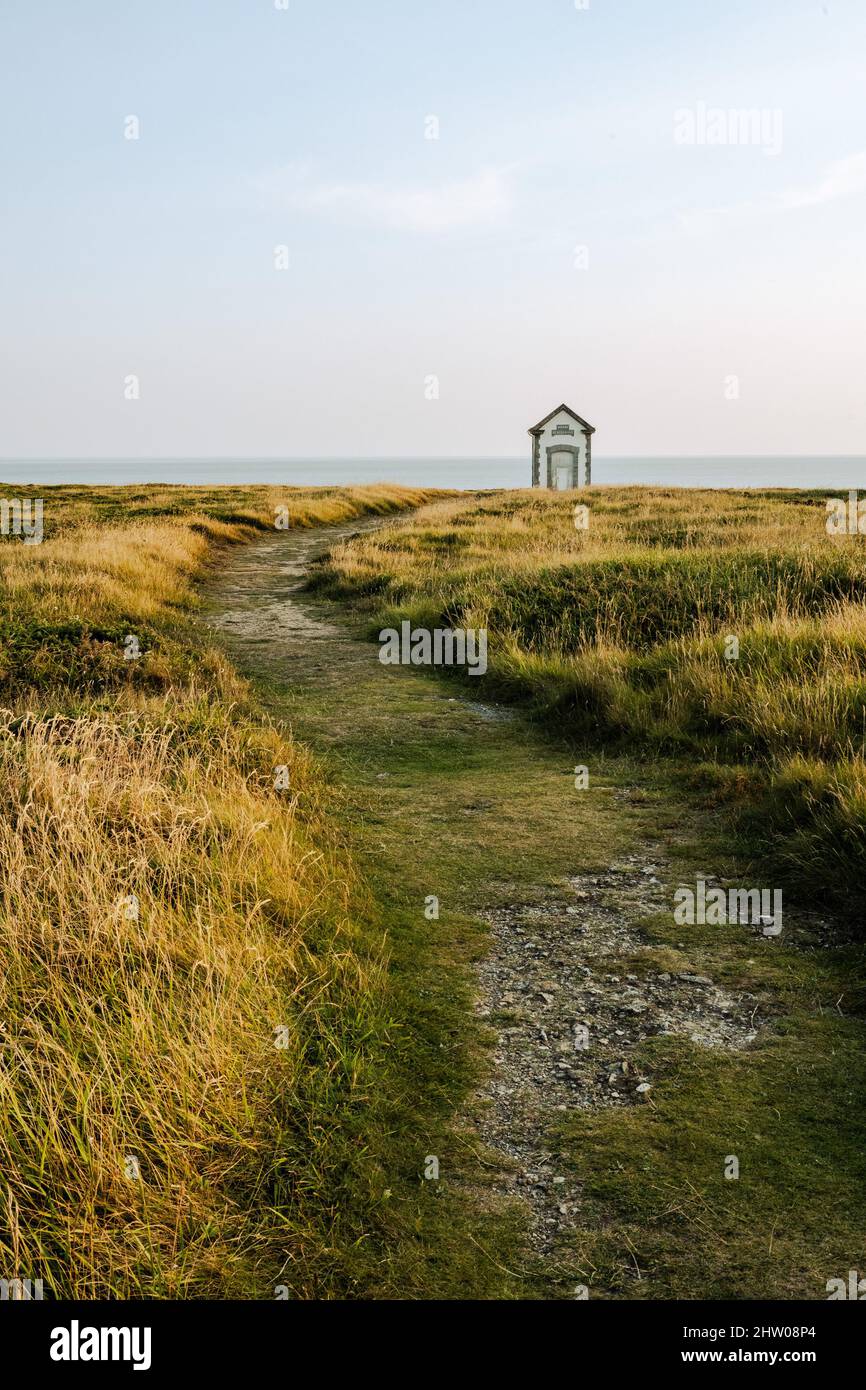 A wide footpath leads through the grass and dune landscape to a small ...