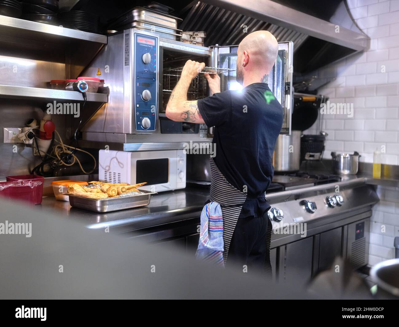 Cook working in a restaurant kitchen preparing the oven Stock Photo - Alamy