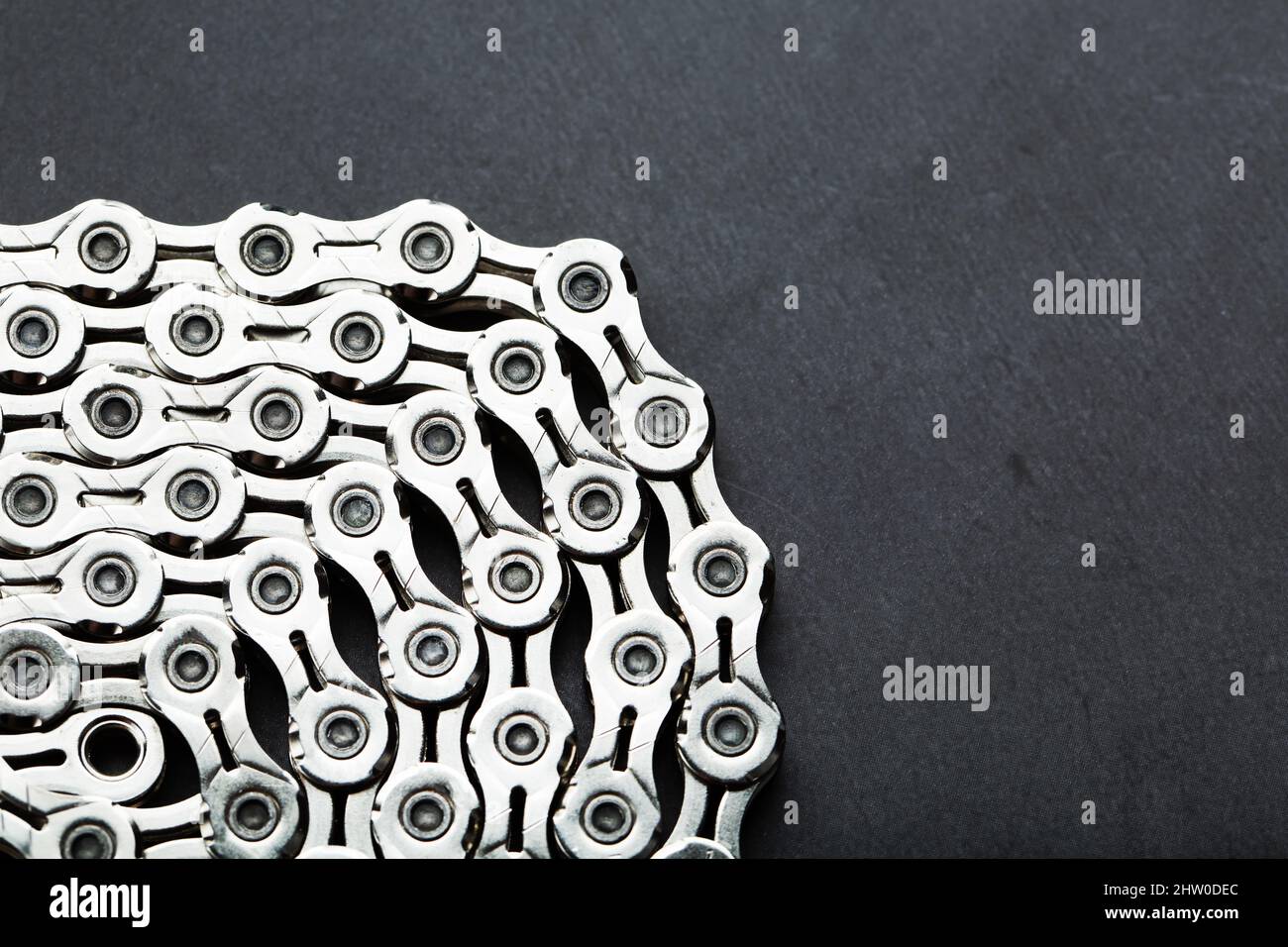 Silver chain of a road bike on a dark textured background with free ...
