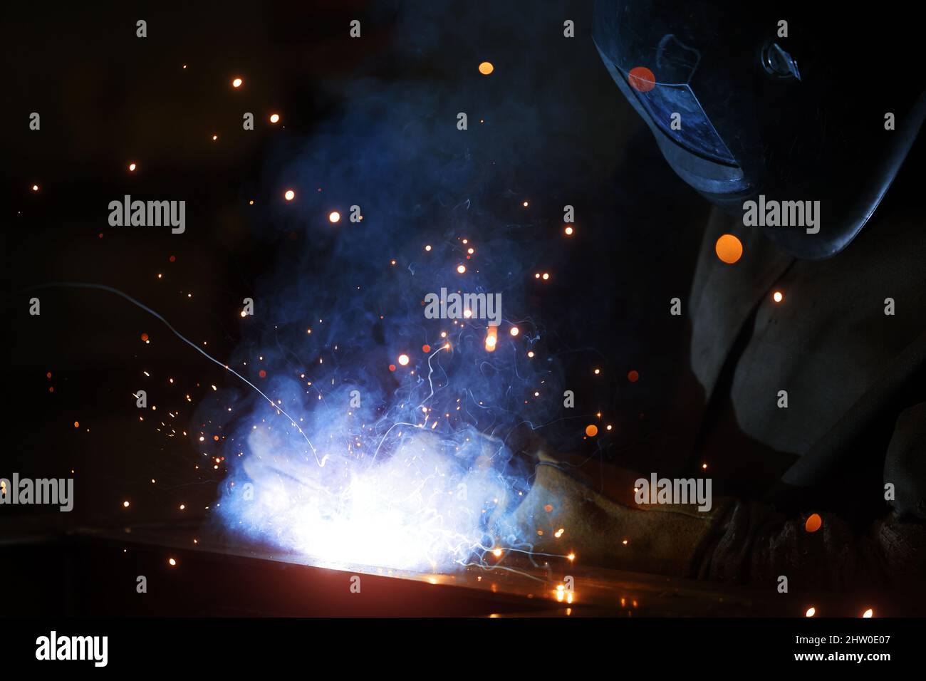 Welder at work. Welding of metal sparks and smoke in the workshop ...