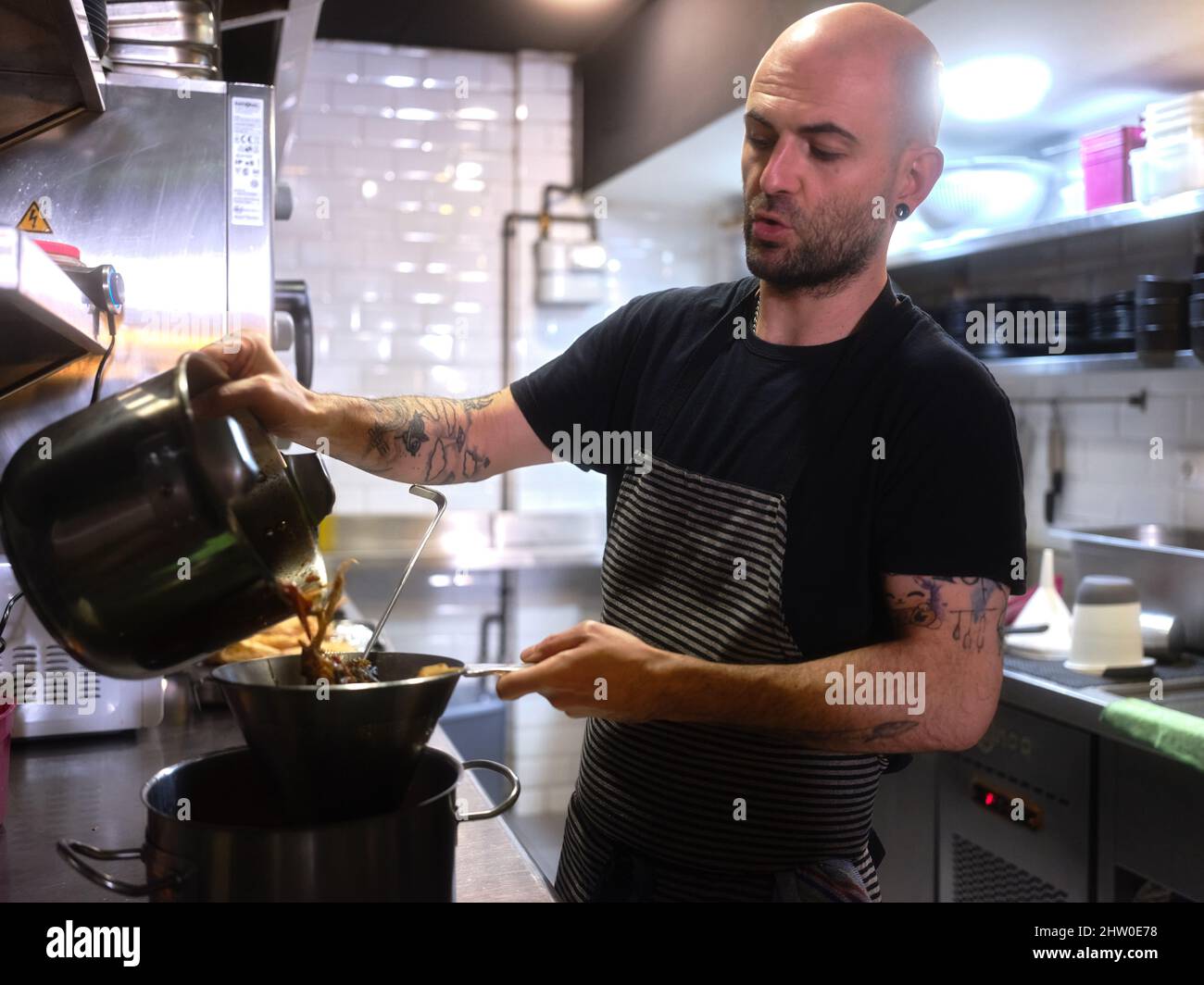 Chef pouring food into a colander in the kitchen of a restaurant Stock ...