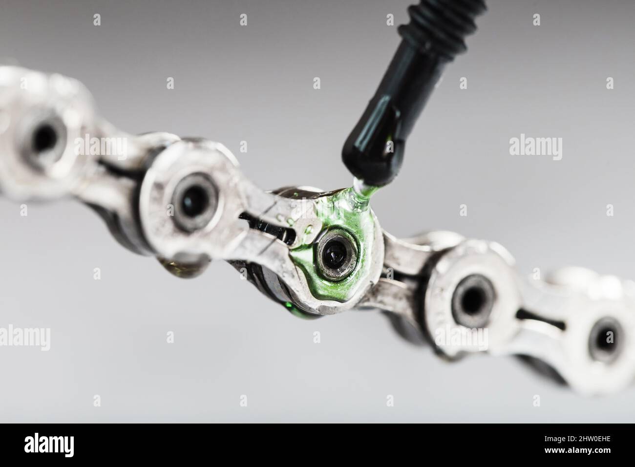 Lubricating a bicycle chain with a drop of oil close-up on an isolated ...