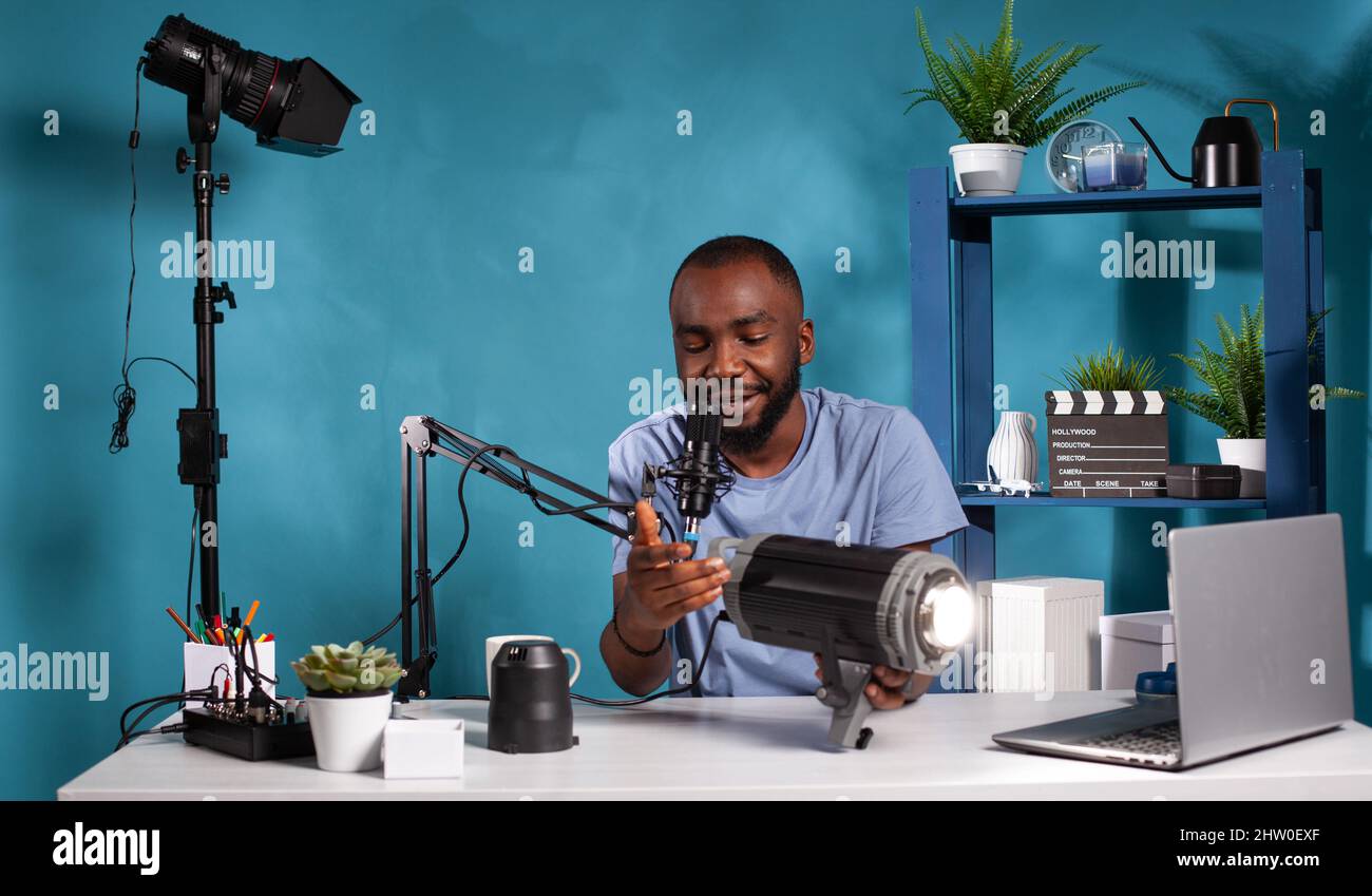 Portrait of african american vlogger looking at new model video light ...