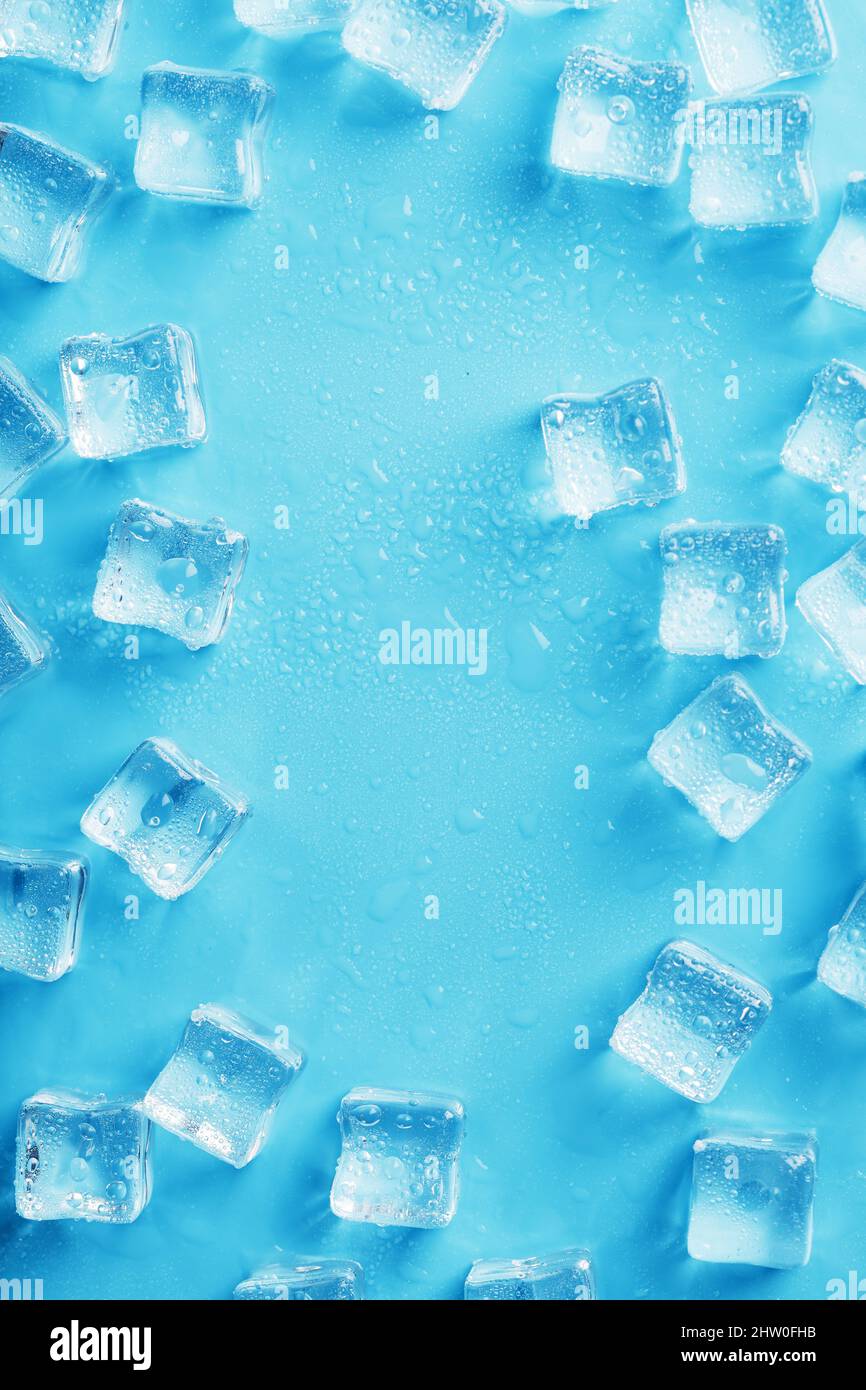 Ice cubes with water drops scattered on a blue background, top view ...