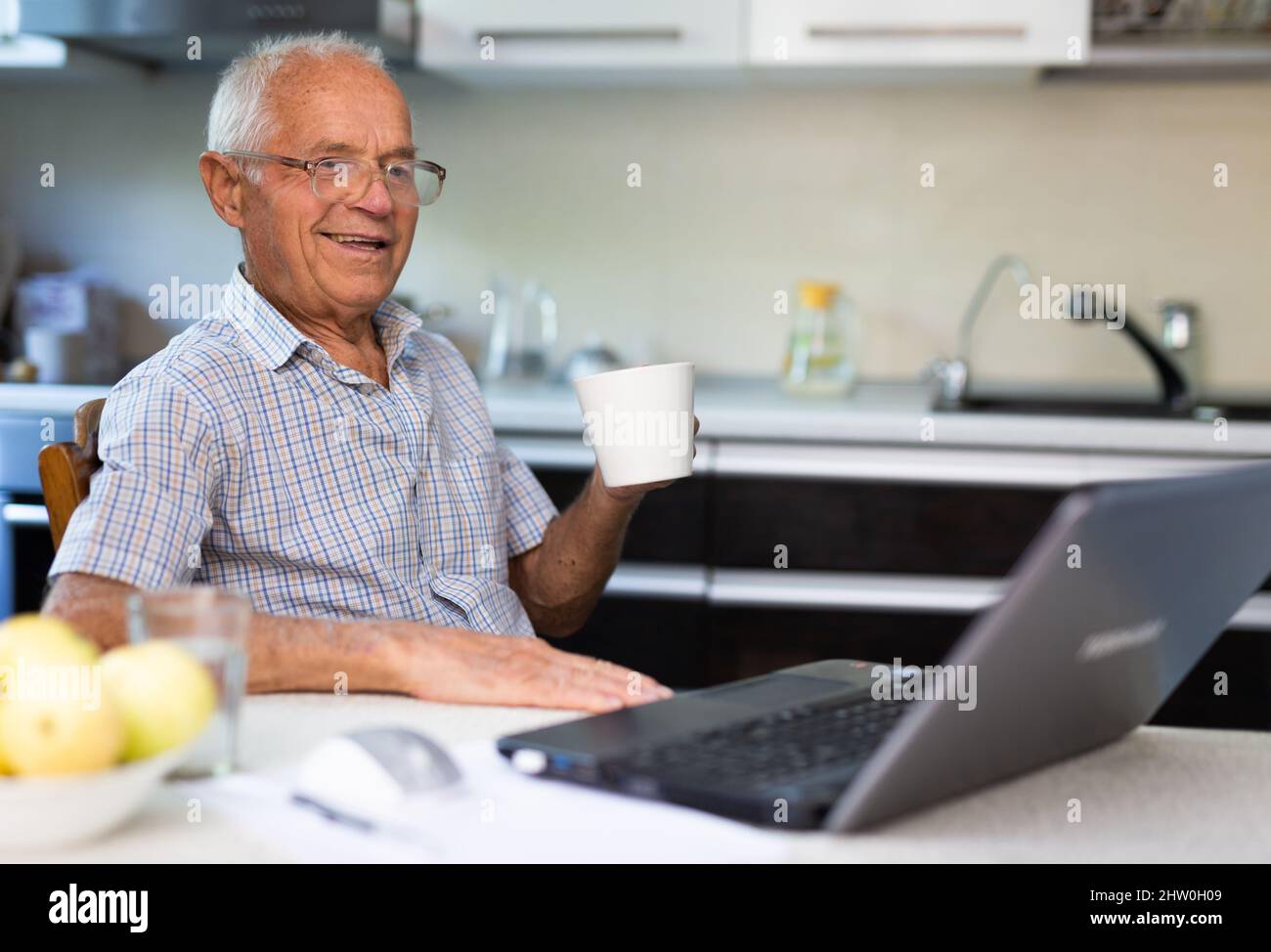 Man looking at screen of laptop while sitting in kitchen Stock Photo ...