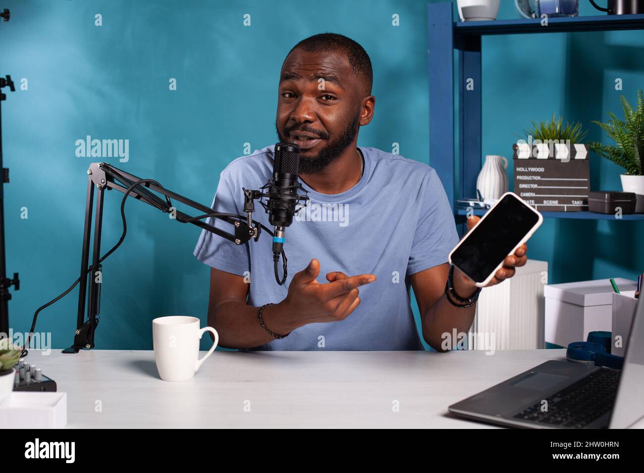 Smiling vlogger holding black screen mockup mobile phone doing online ...