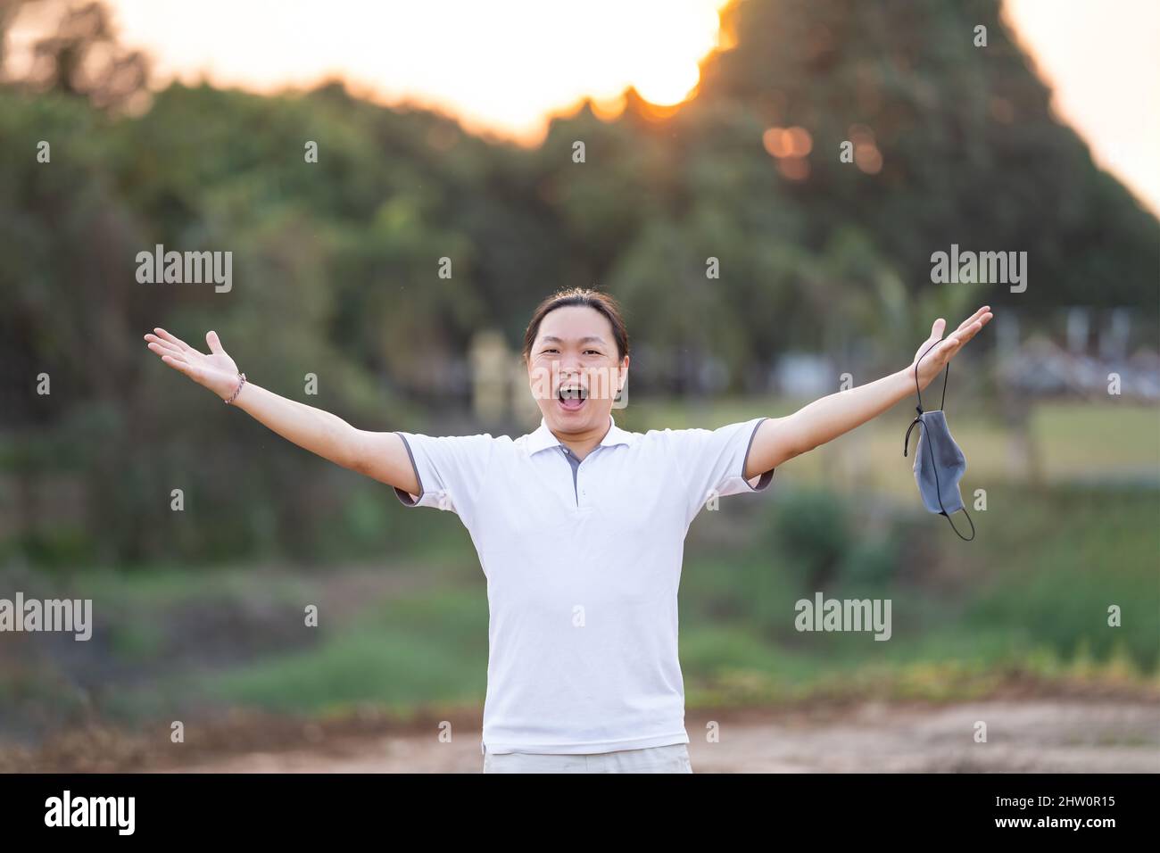 Asian Man take off mask and rise his hand up in golden twilight time ...
