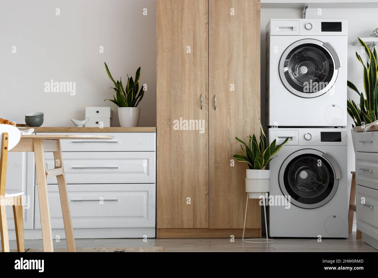 Interior of light kitchen with washing machines, white counters and ...