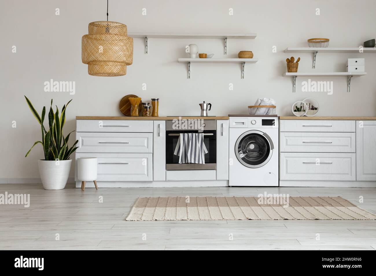 Interior of light kitchen with washing machine, oven and white counters ...